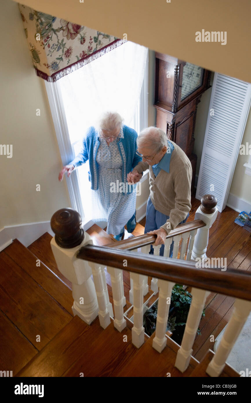 Senior couple helping one another carefully climb up stairs Stock Photo ...