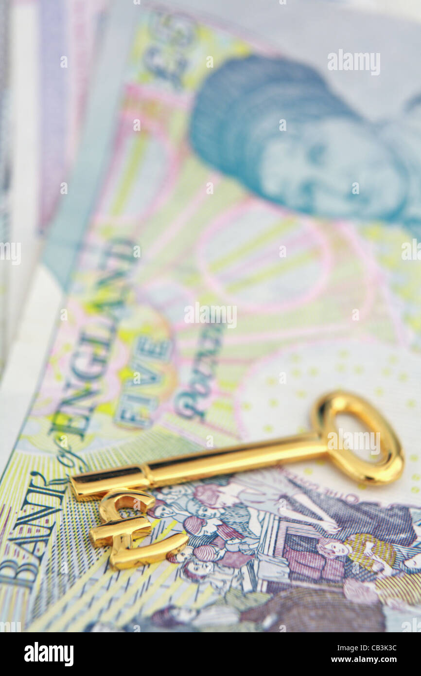A gold key with the pound currency symbol lying on euro banknotes, a ...