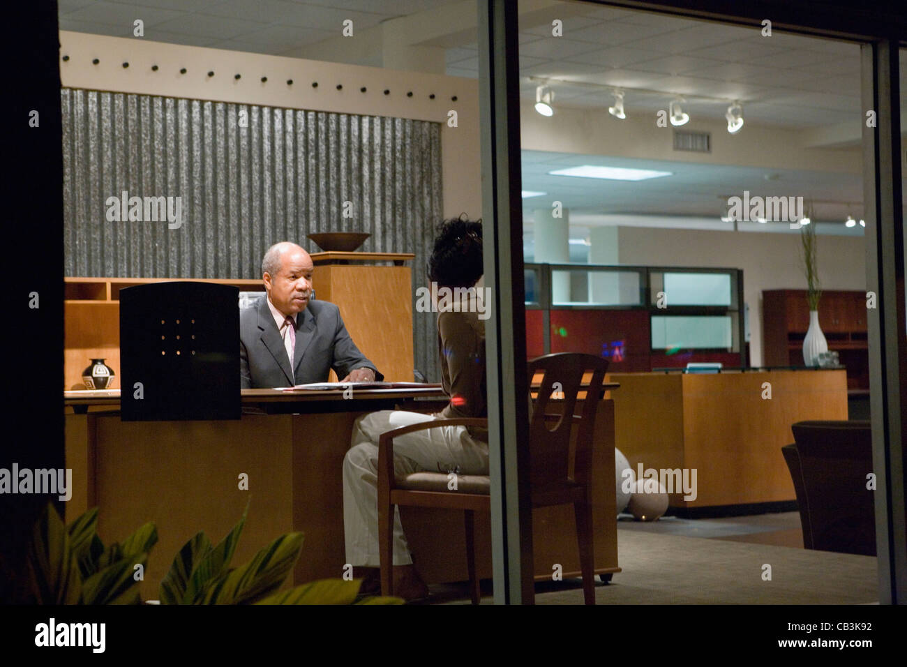 View through window of man and woman talking in an office Stock Photo ...