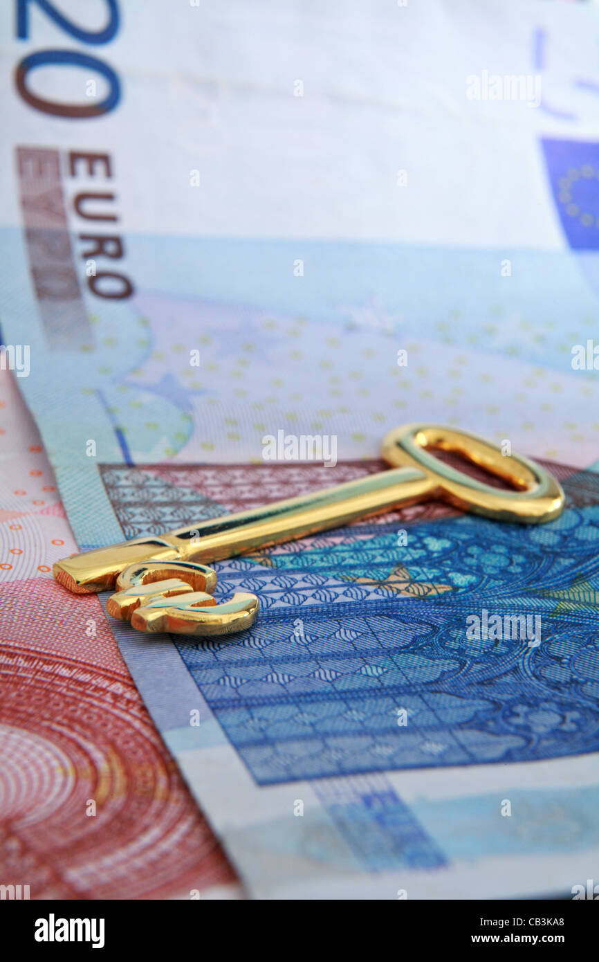 A gold key with the euro currency symbol lying on euro banknotes, a ...