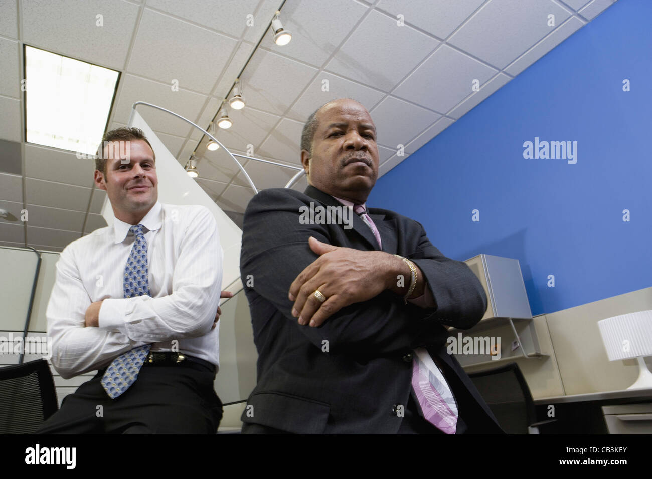 Portrait of a serious manager thinking while younger office worker ...