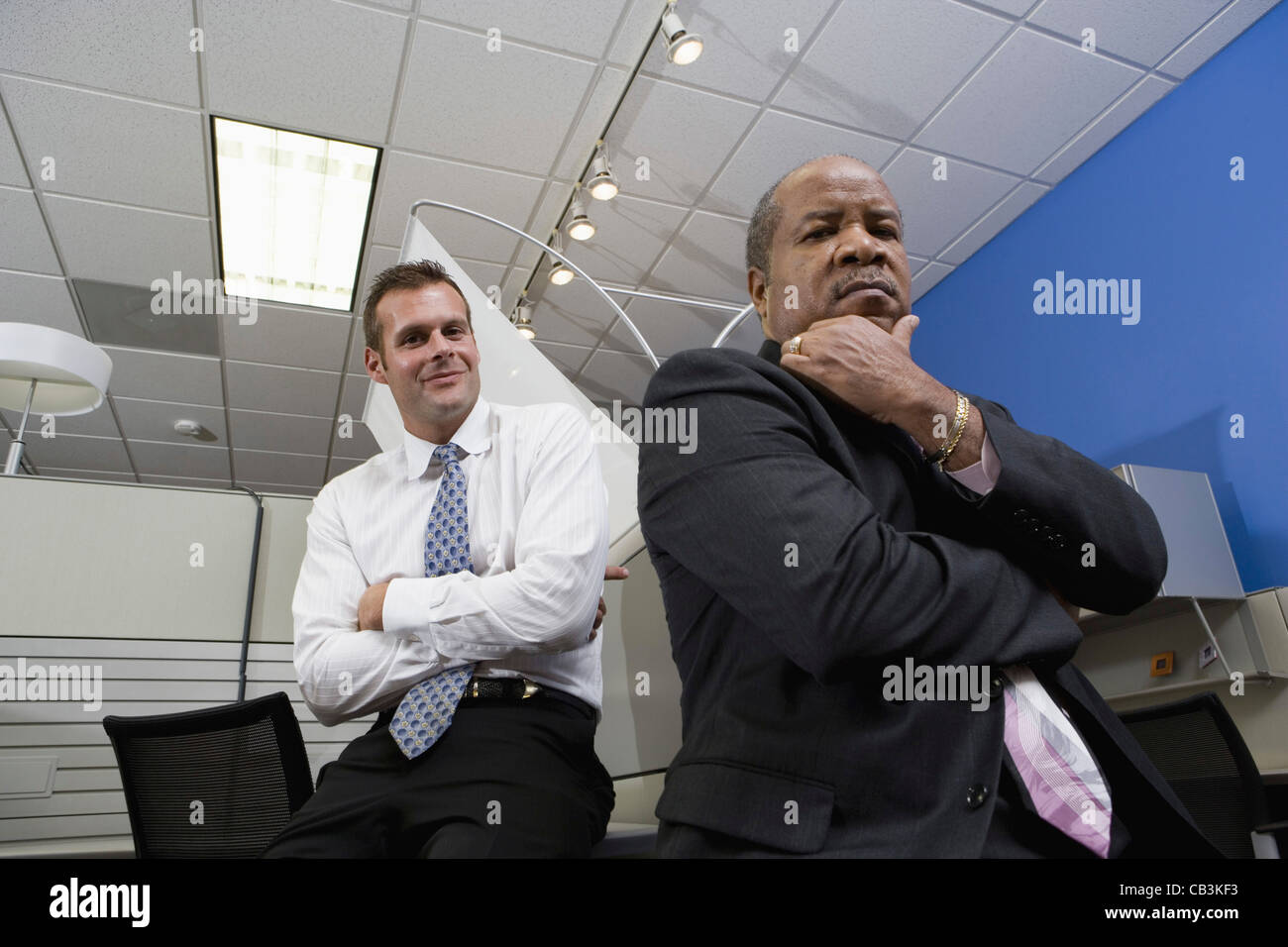 Portrait of a serious manager thinking while younger office worker ...