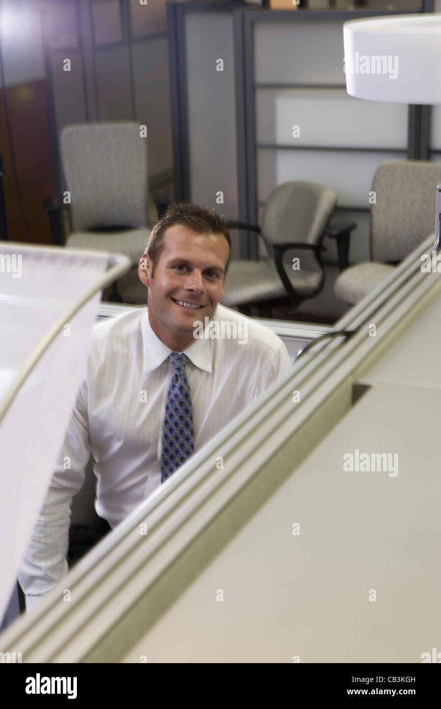 Portrait of a smiling young man looking over his cubicle wall Stock ...