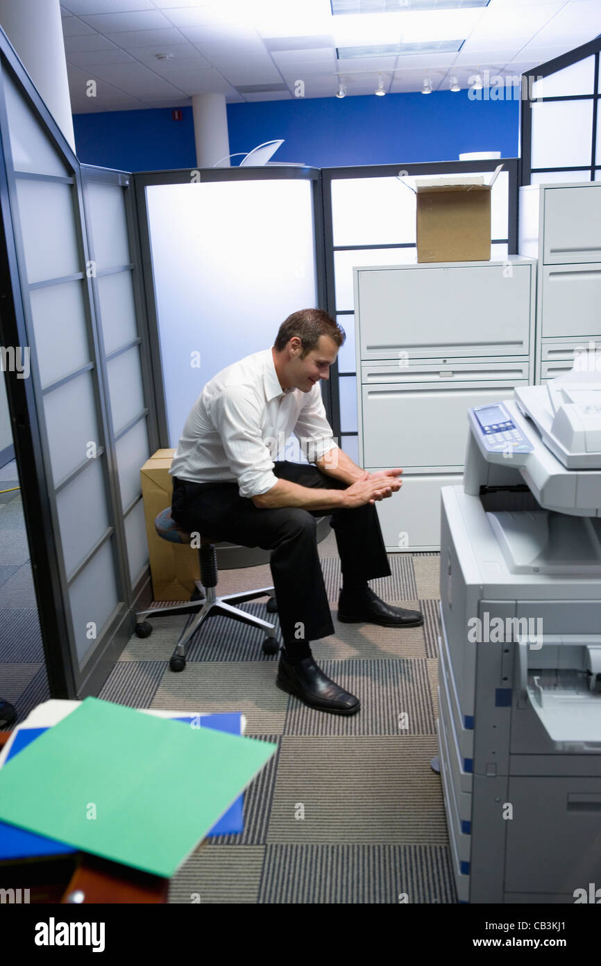 Office worker sitting alone by the copy machine Stock Photo - Alamy
