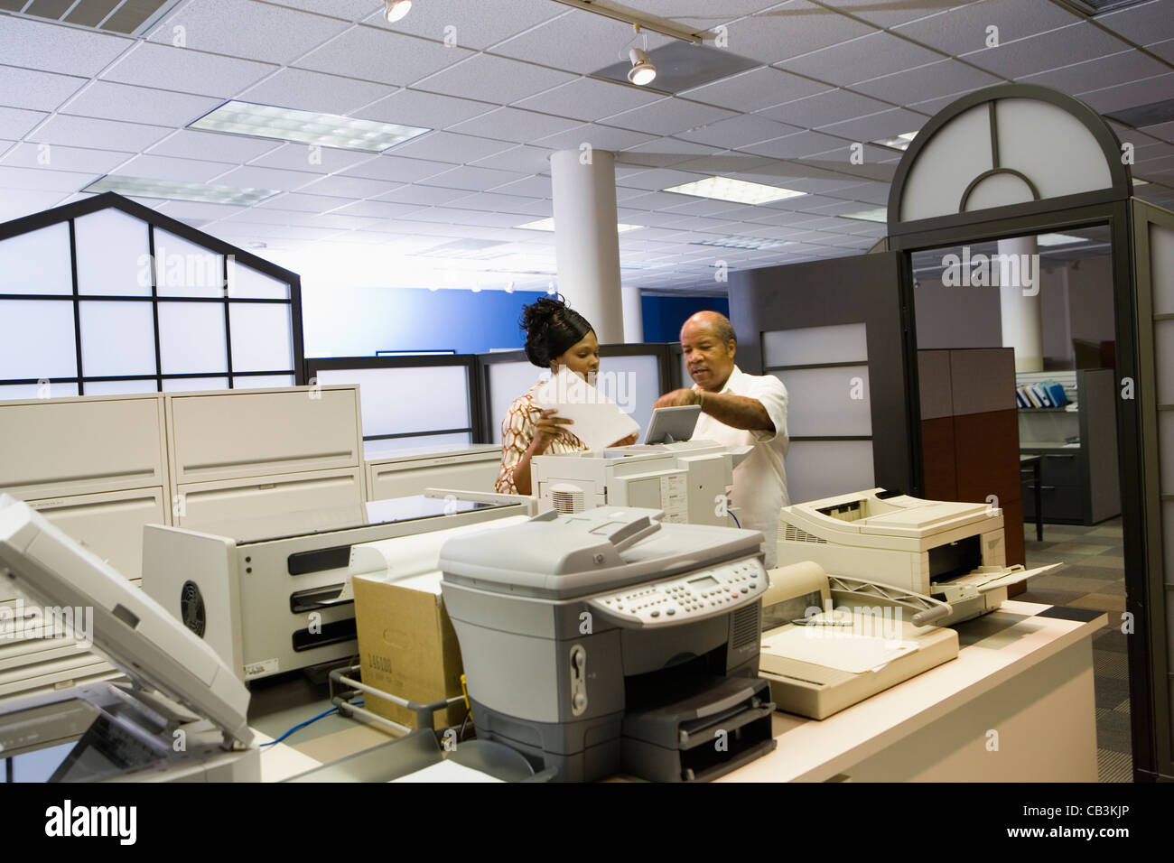 Co-workers using office equipment Stock Photo - Alamy