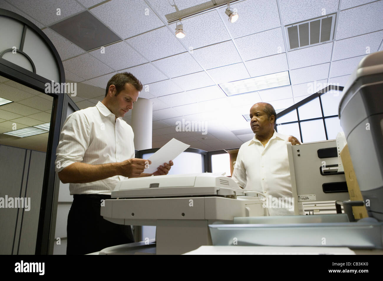 Co-workers using office equipment Stock Photo - Alamy