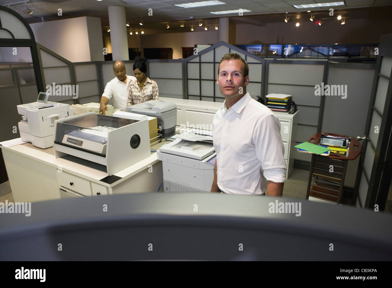View over an cubicle wall of office workers by copy machines Stock ...
