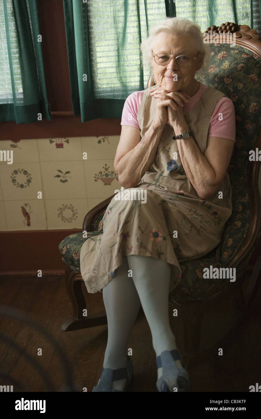 A smiling senior woman sitting on a chair Stock Photo - Alamy