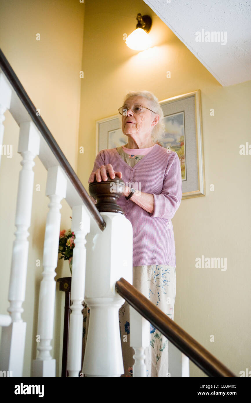 Senior woman standing by staircase alone, looking up the stairs Stock ...