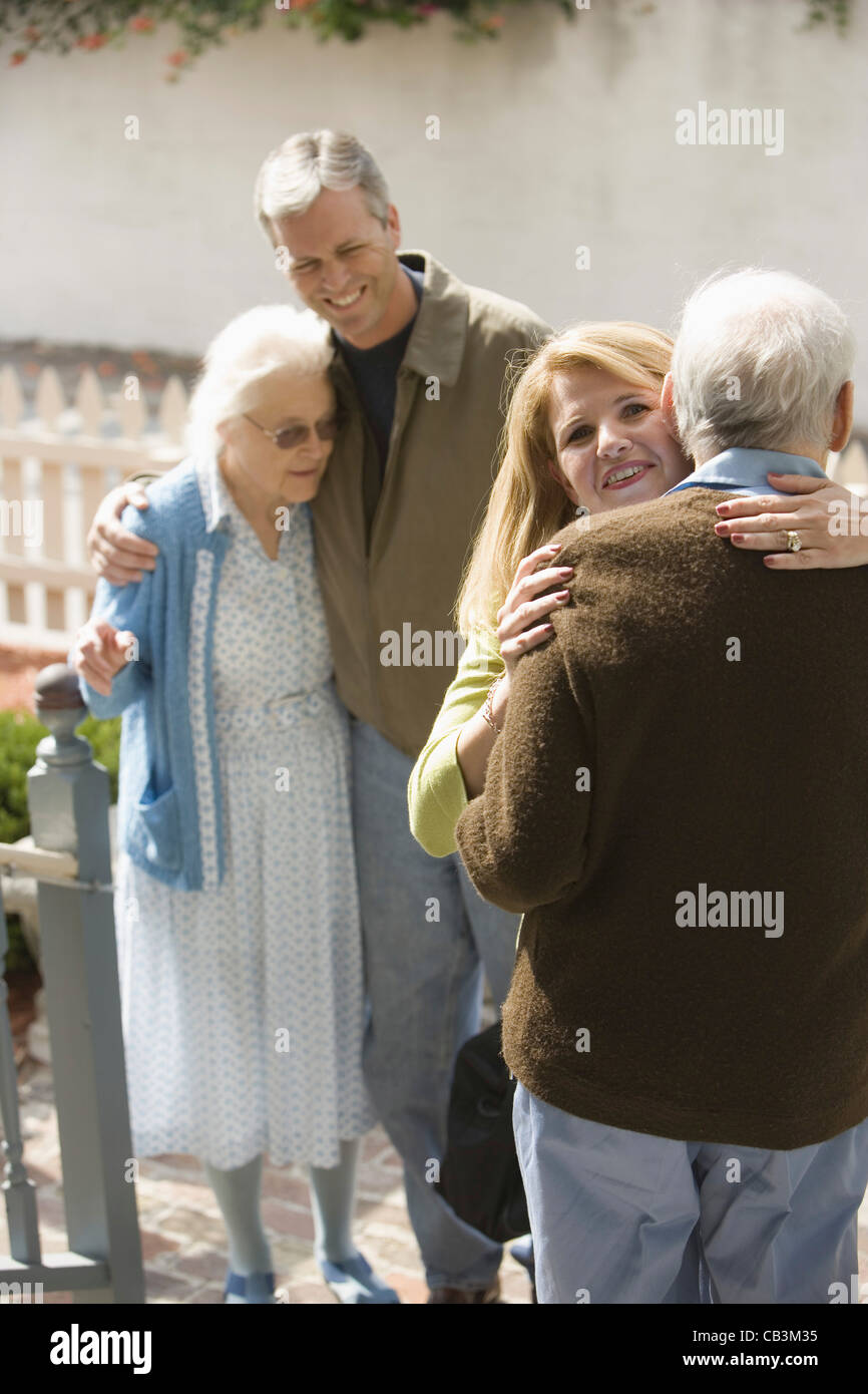 Woman hugging senior man while man and senior woman watch Stock Photo ...