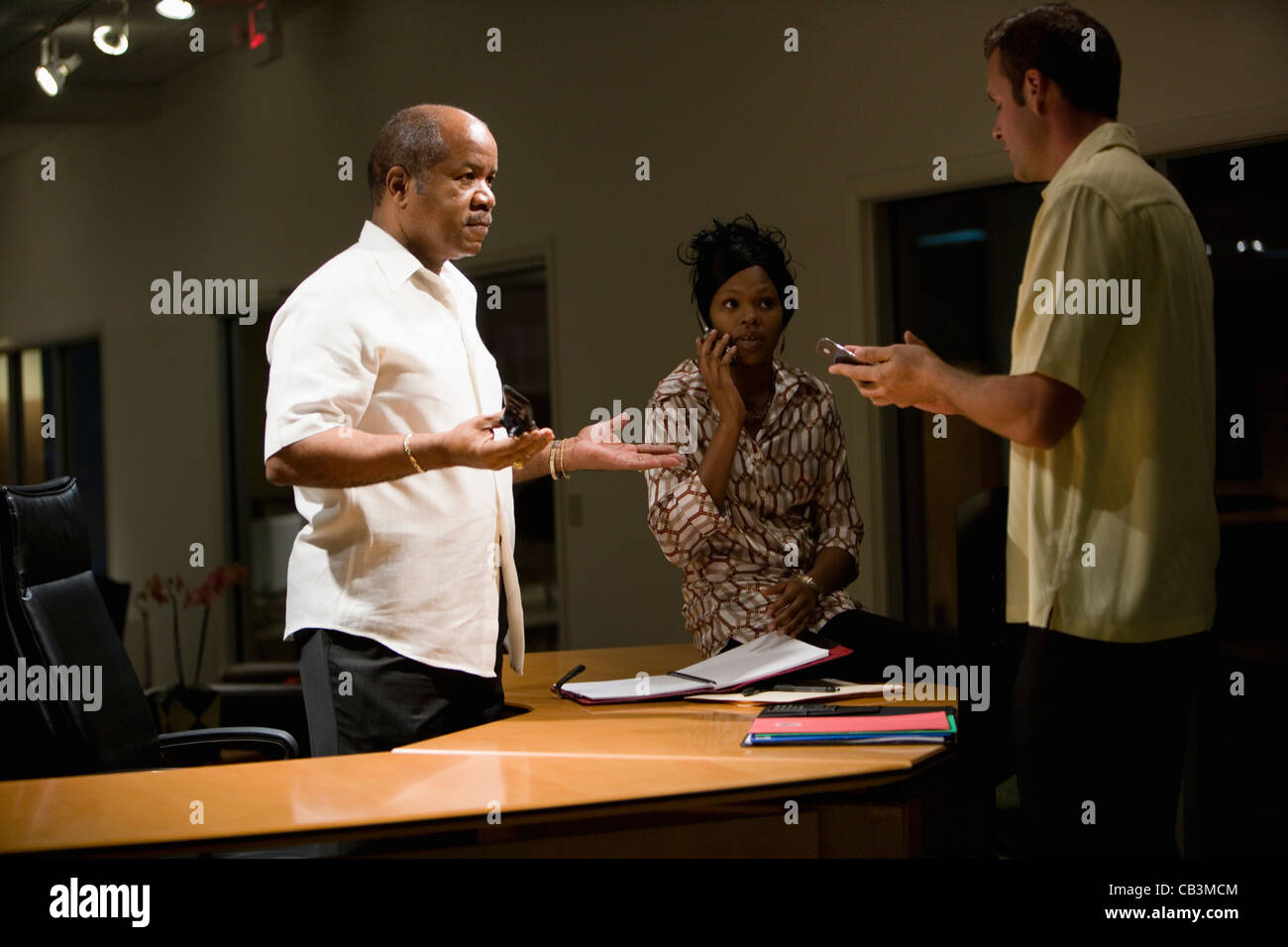 Mature businessman standing behind desk conversing with younger ...