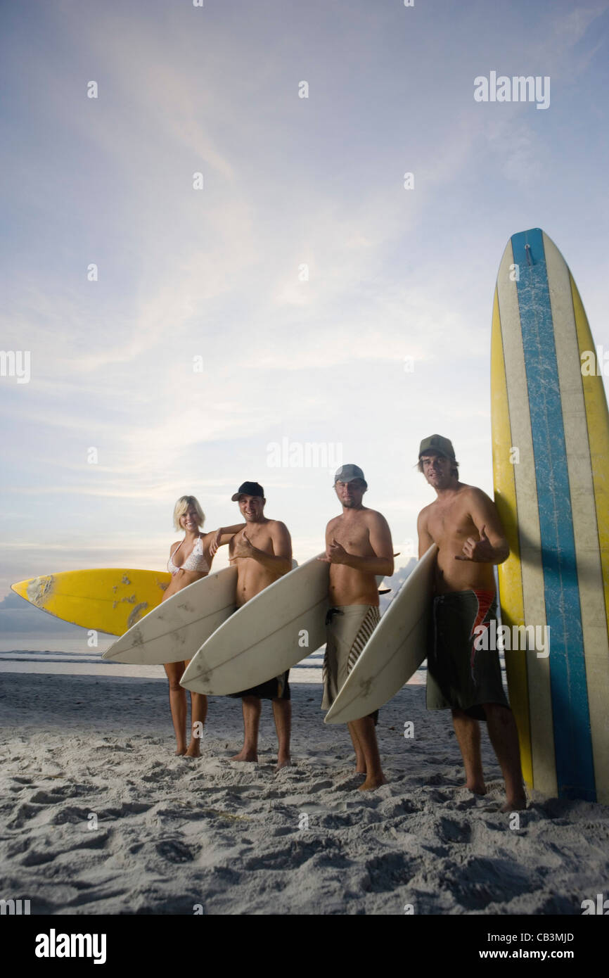 Surfer dudes and girl posing on beach at sunrise with surfboards Stock ...