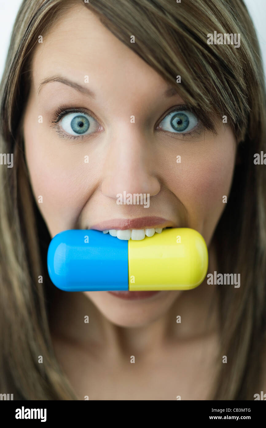 Portrait of young woman biting large capsule pill Stock Photo - Alamy