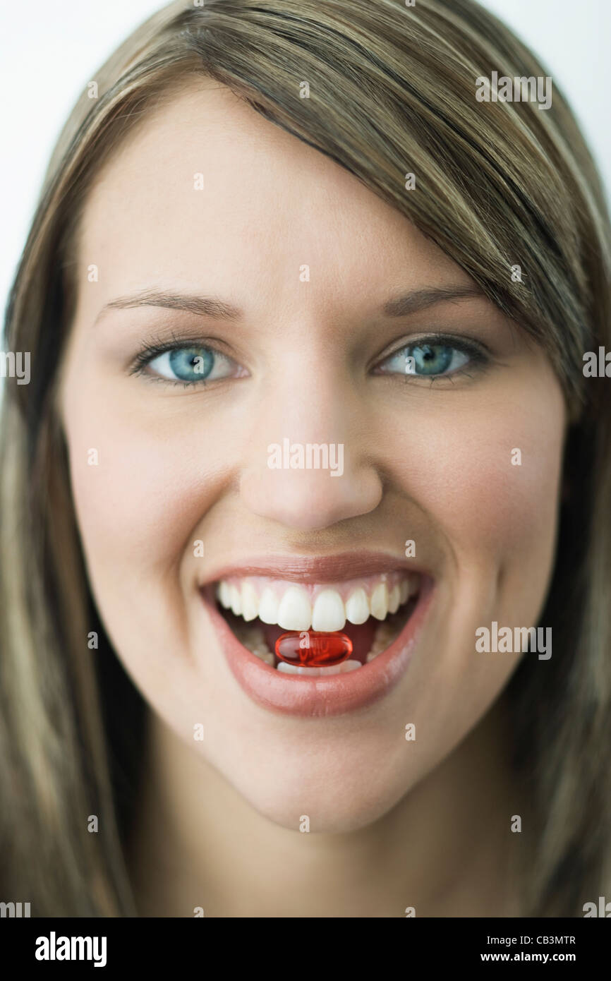 Portrait of young woman biting capsule pill Stock Photo - Alamy