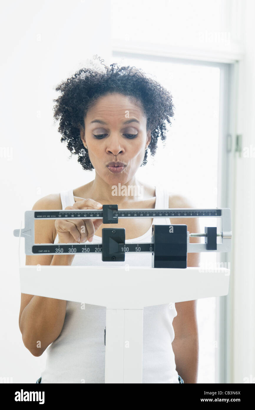 Mid adult woman measuring her weight on a weighing scale Stock Photo ...