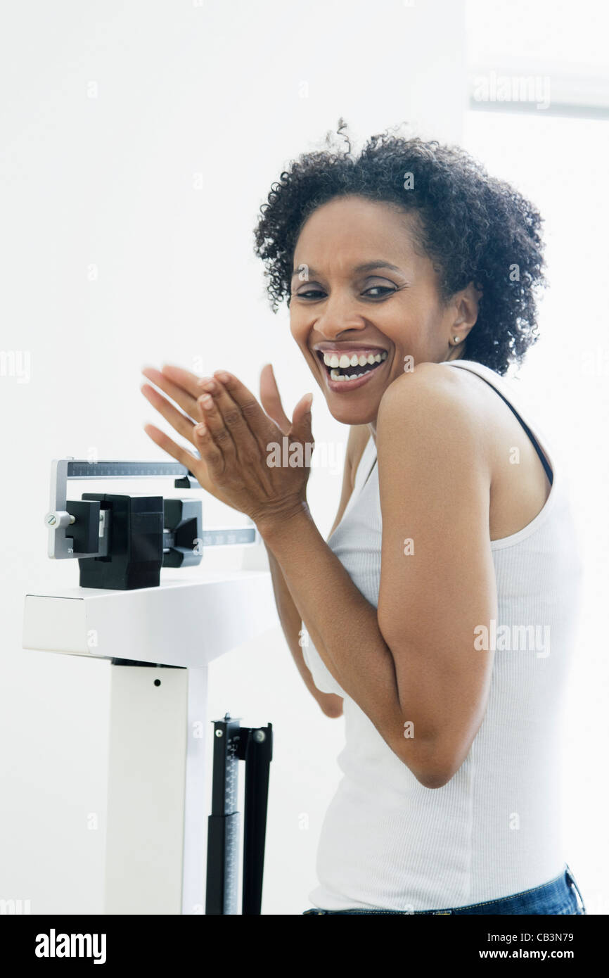 Mid adult woman measuring her weight on a weighing scale Stock Photo ...