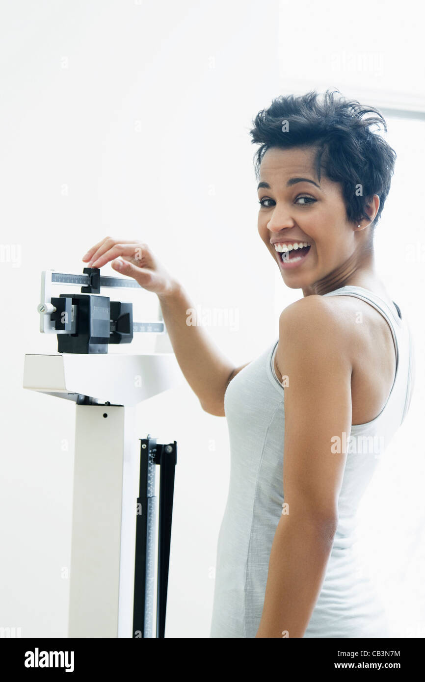 Mid adult woman measuring her weight on a weighing scale Stock Photo ...