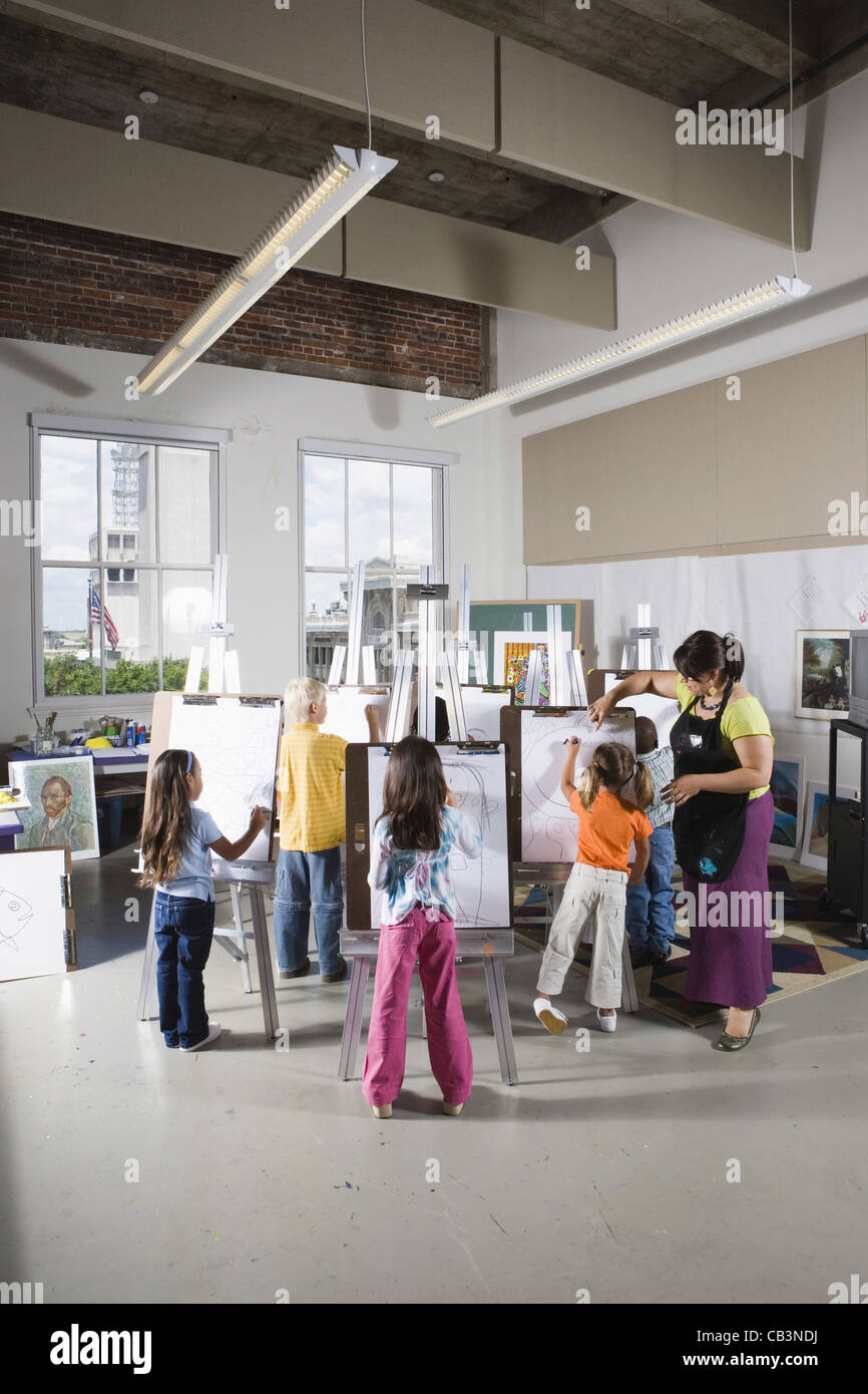 An art teacher with her students drawing on easels in art class Stock Photo - Alamy