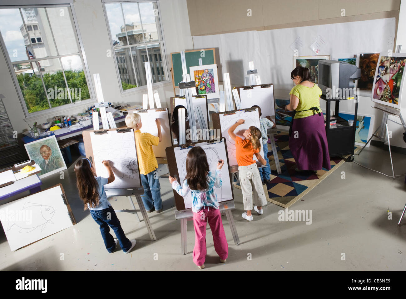 An art teacher with her students drawing on easels in art class Stock ...