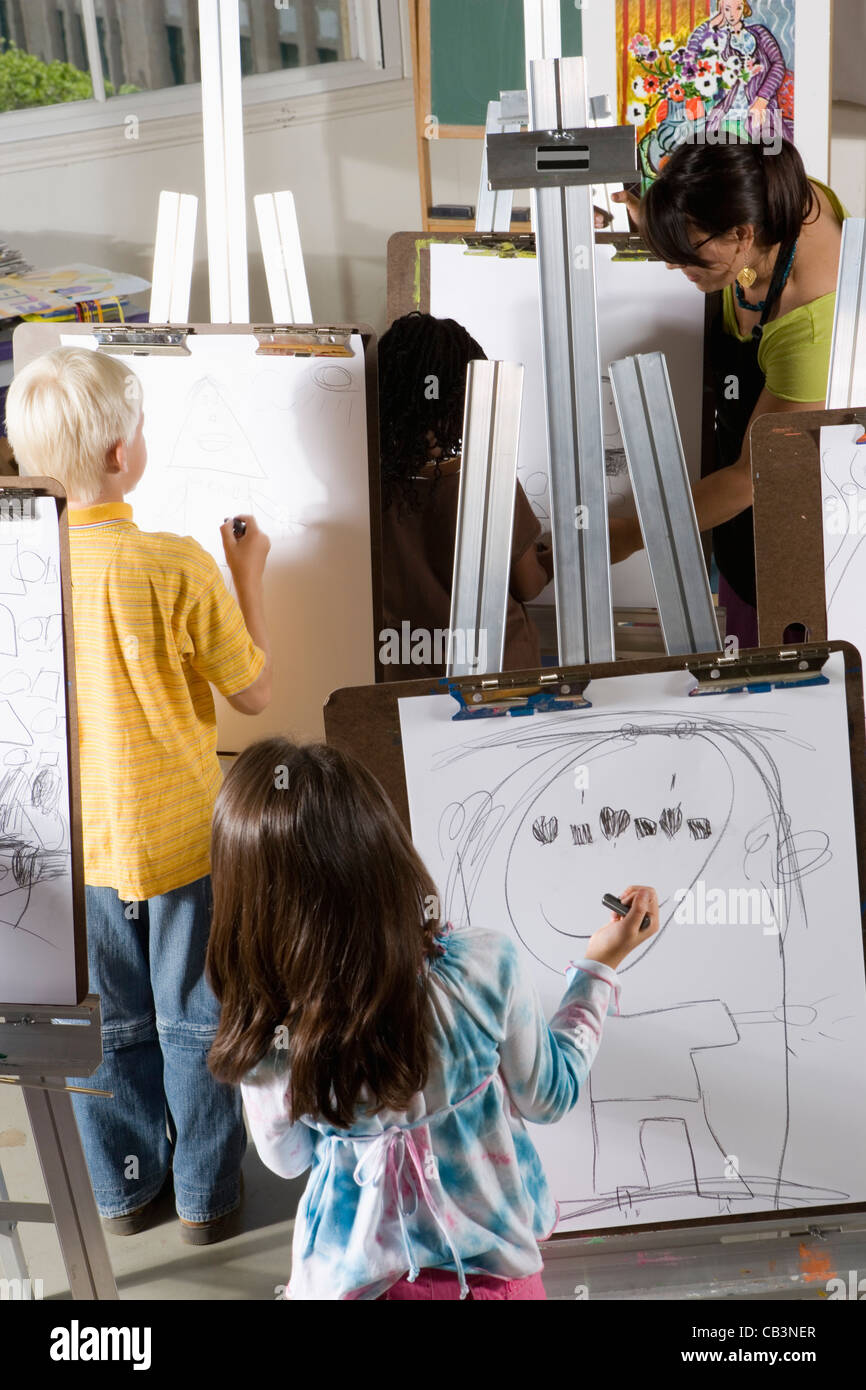 An art teacher with her students drawing on easels in art class Stock ...