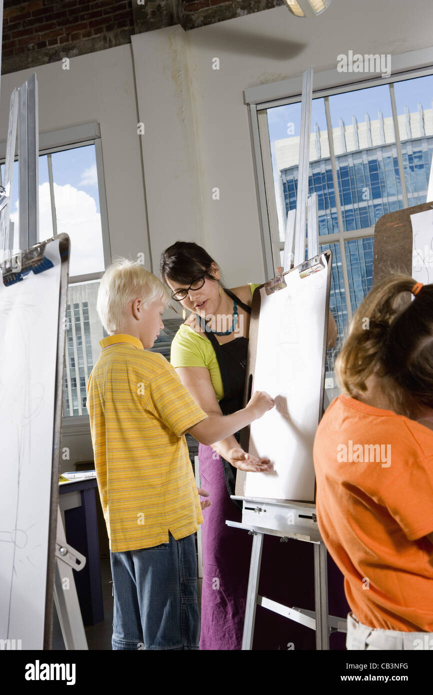 An art teacher with her students drawing on easels in art class Stock Photo - Alamy