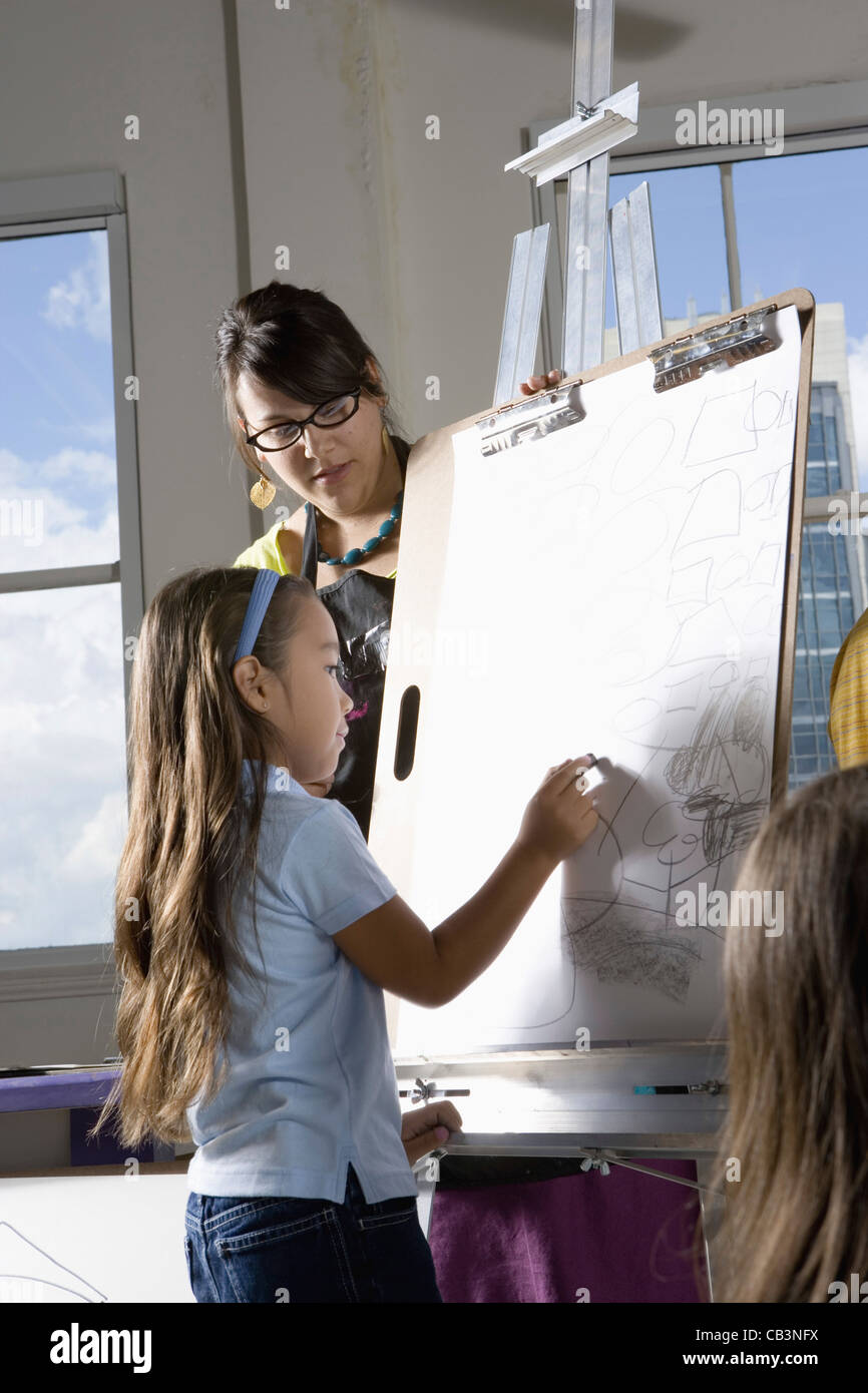 An art teacher with her students drawing on easels in art class Stock ...