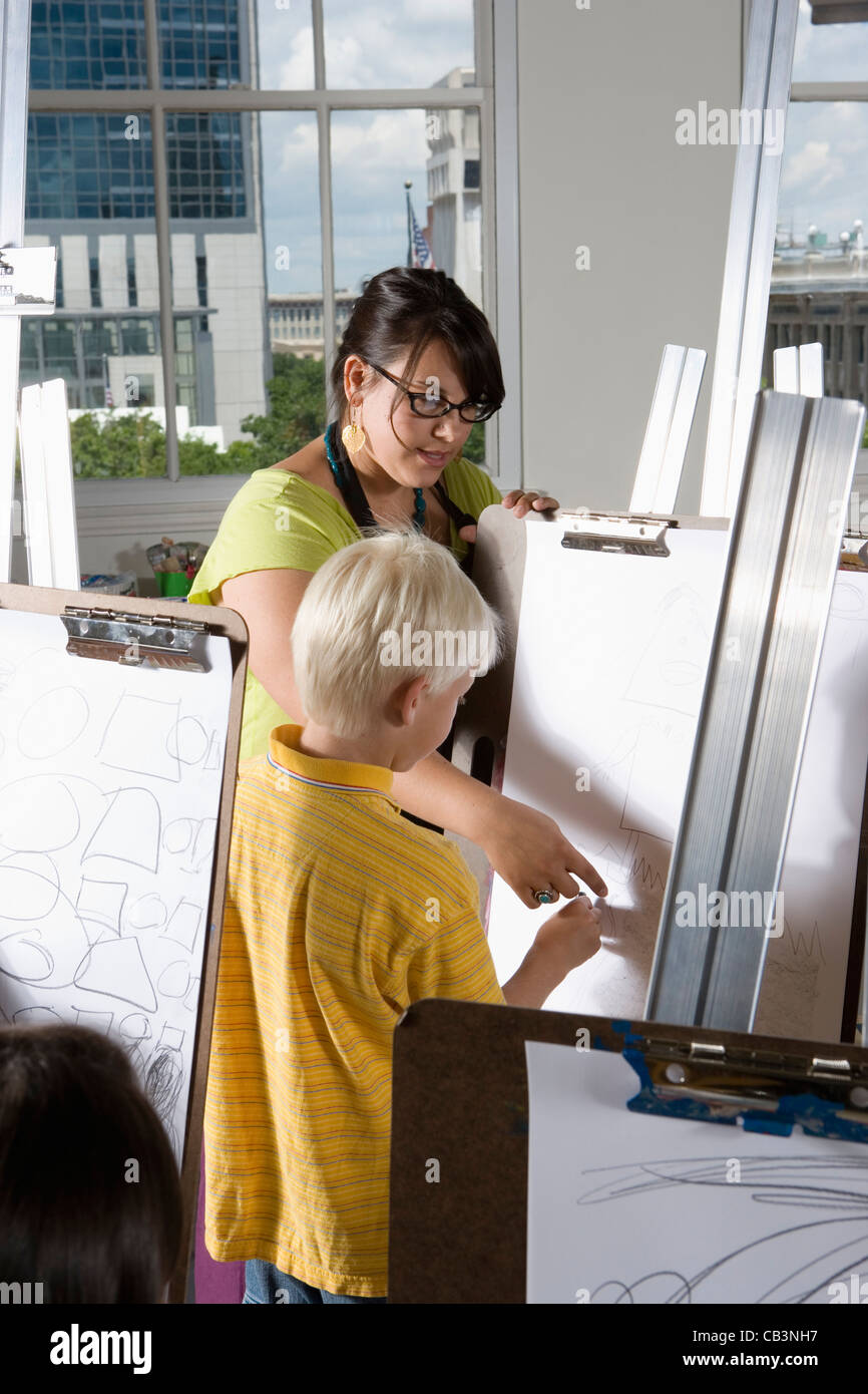 An art teacher with her student drawing on easels in art class Stock Photo - Alamy