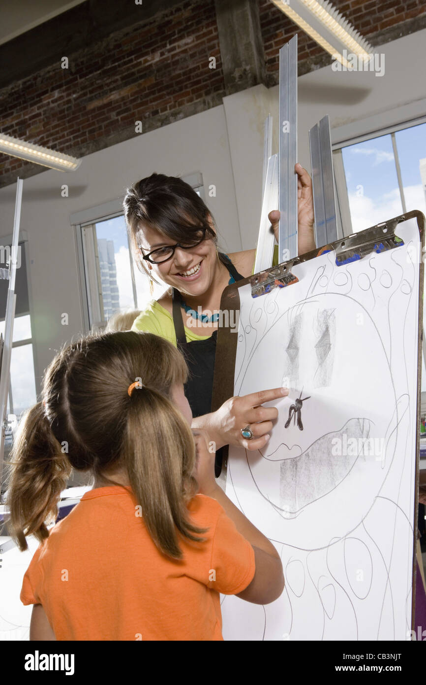 An art teacher with her student drawing on easel in art class Stock ...