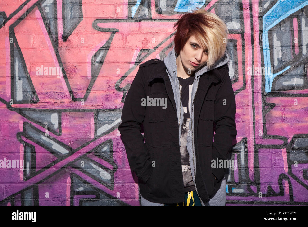 Portrait of punk girl standing by graffiti wall Stock Photo - Alamy