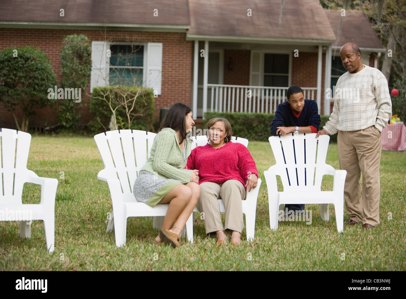 Family and friend relaxing in backyard conversing Stock Photo - Alamy