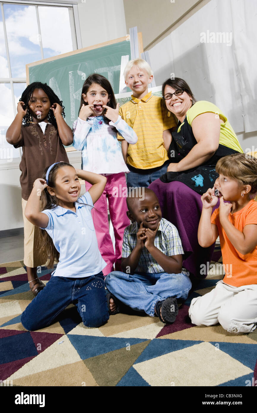 Portrait of an art teacher posing with her students making funny faces ...