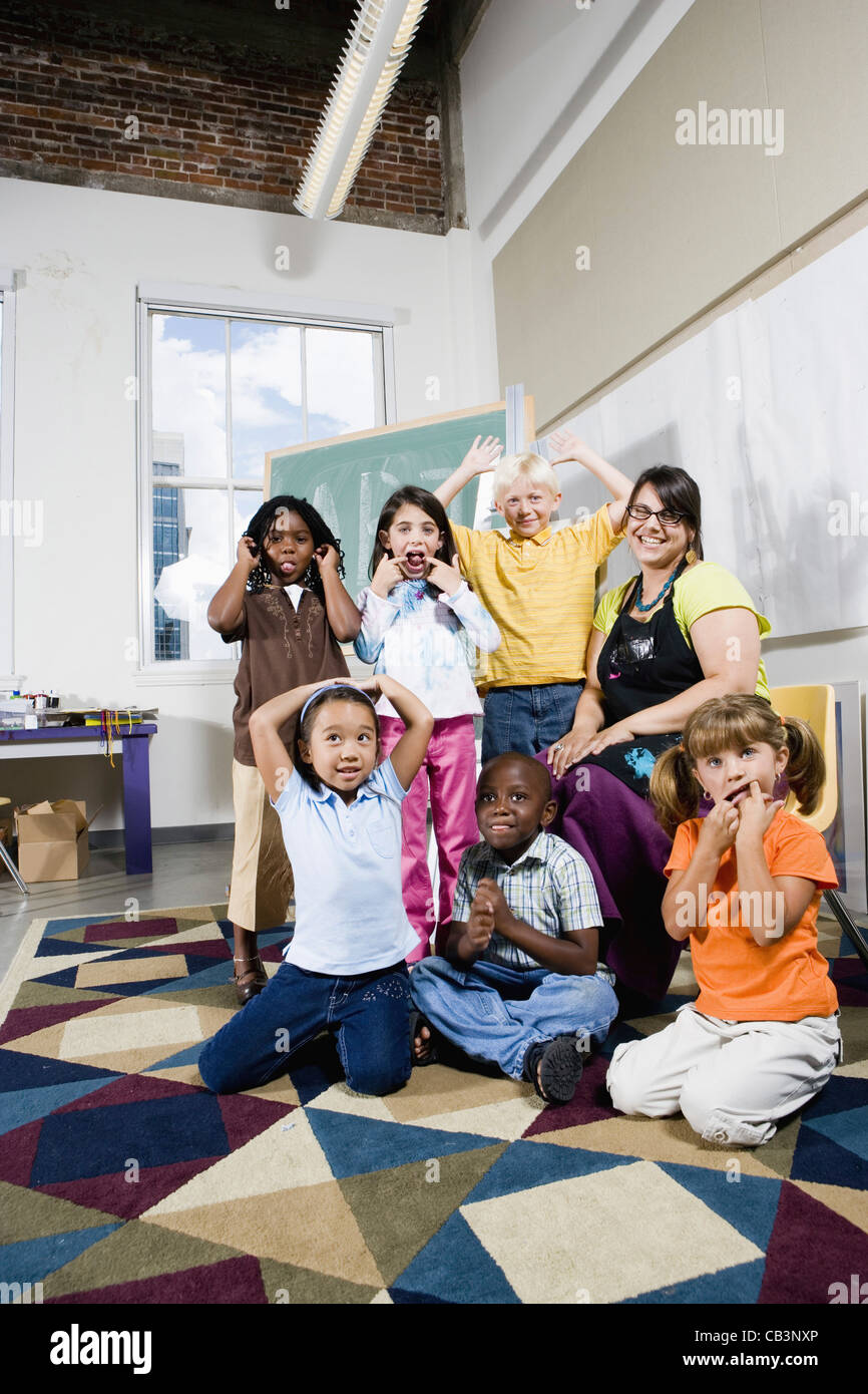 Portrait of an art teacher posing with her students making funny faces ...