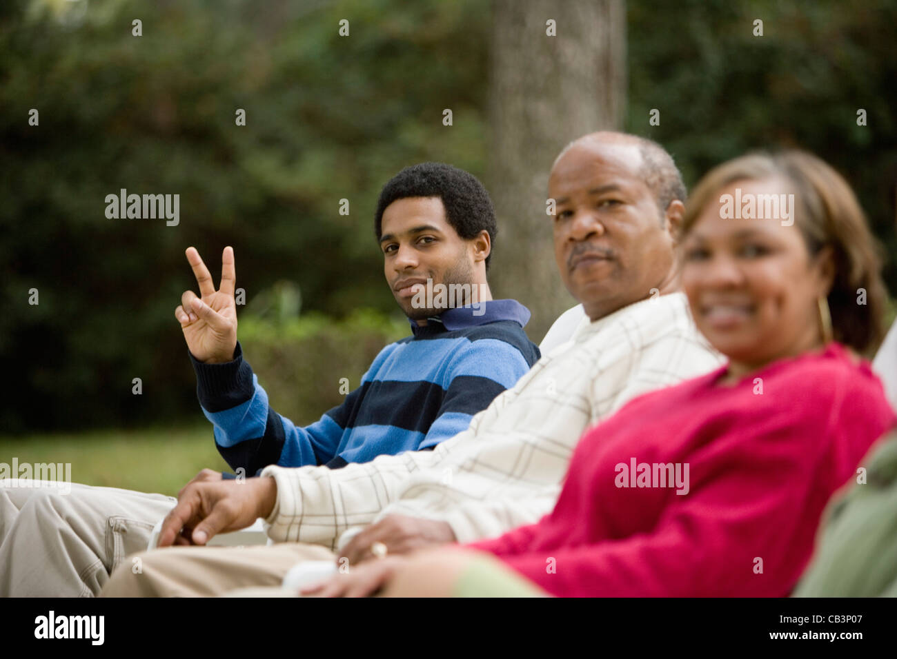 Son giving peace sign with parents in foreground Stock Photo - Alamy