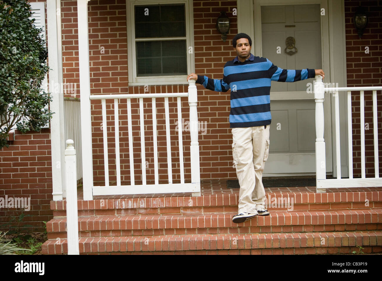 Portrait of a young man standing on front porch of house Stock Photo ...