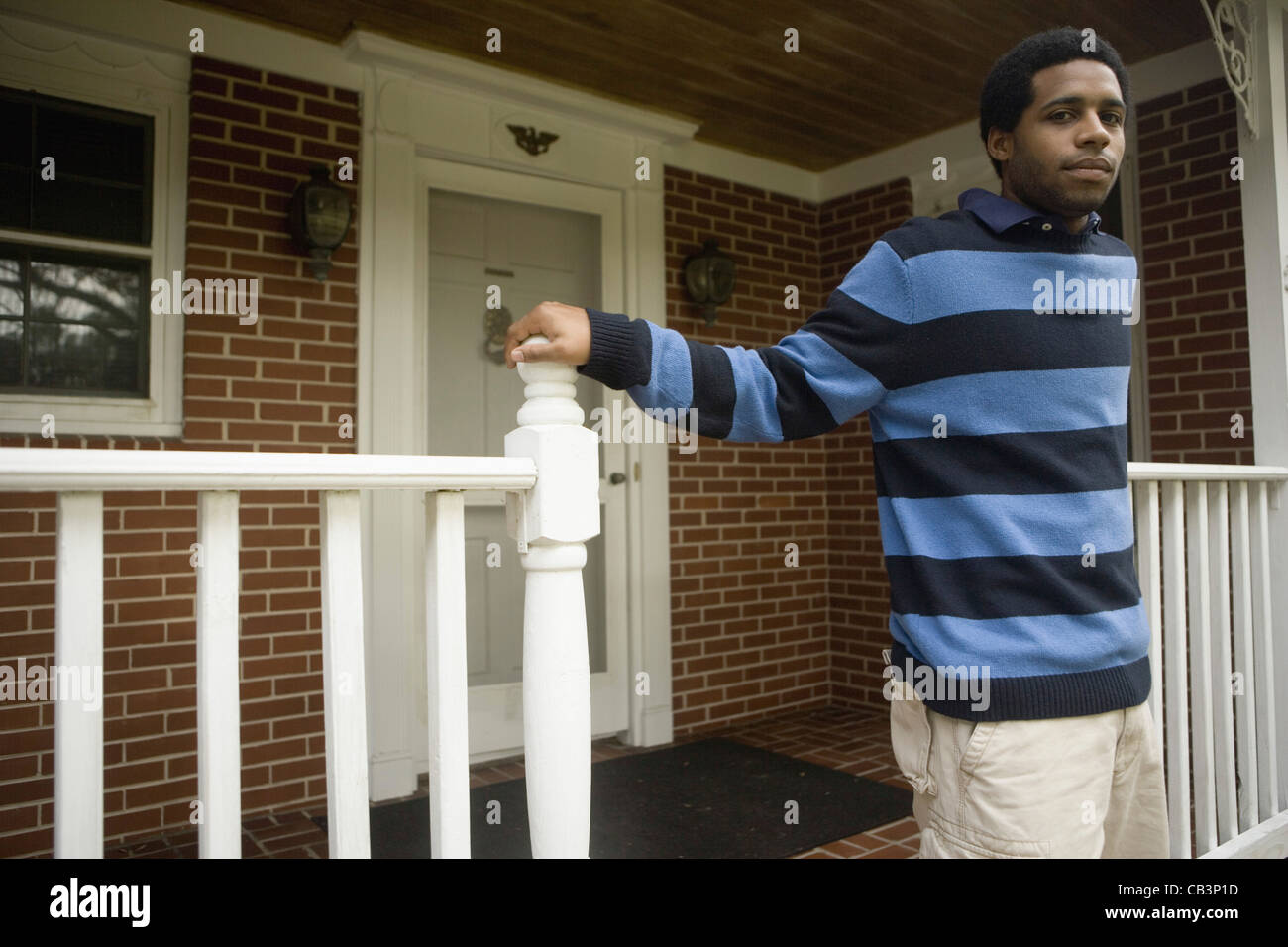Portrait of a young man standing on front porch of house Stock Photo ...