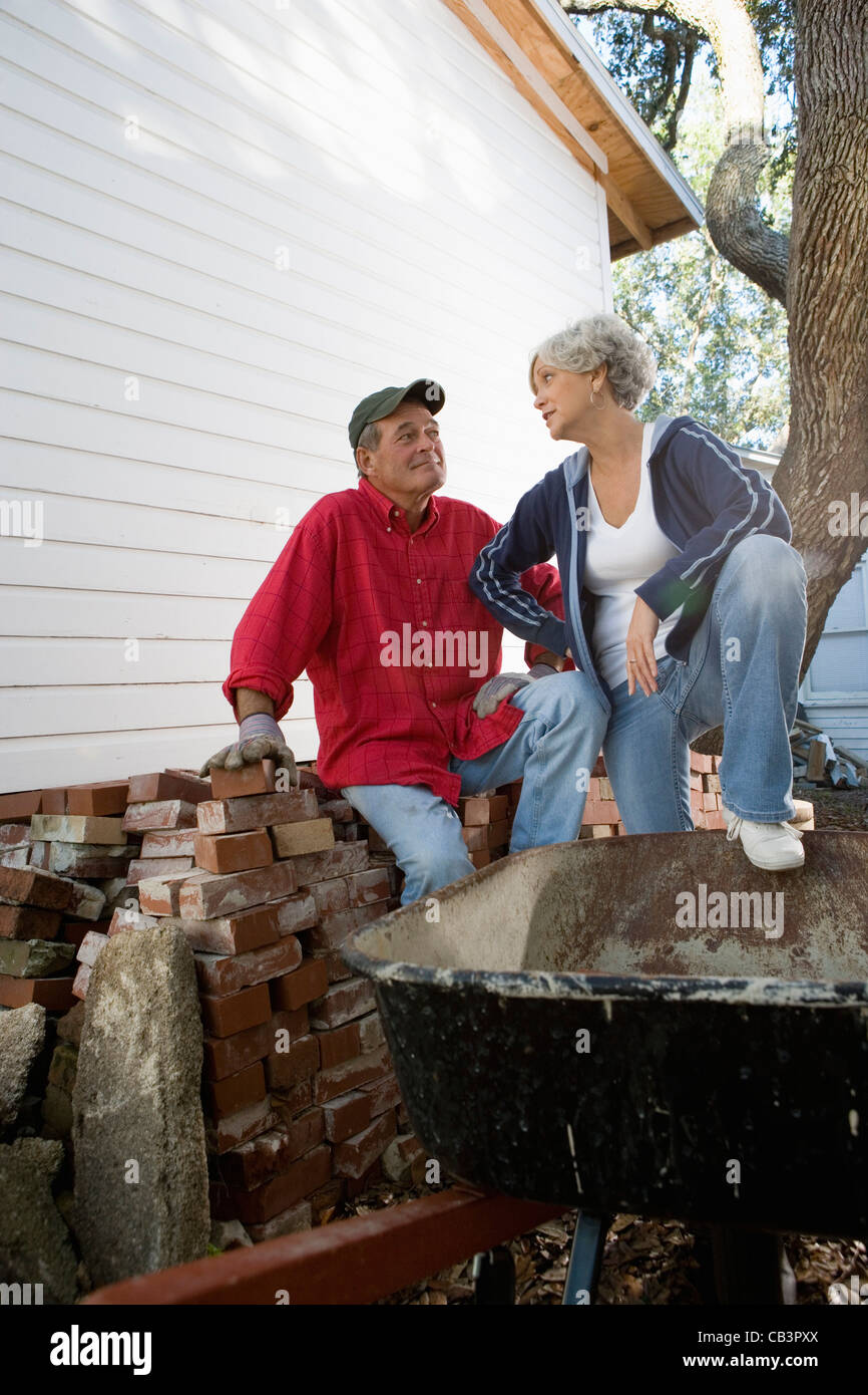 Mature couple conversing next to stack of bricks outside house Stock ...