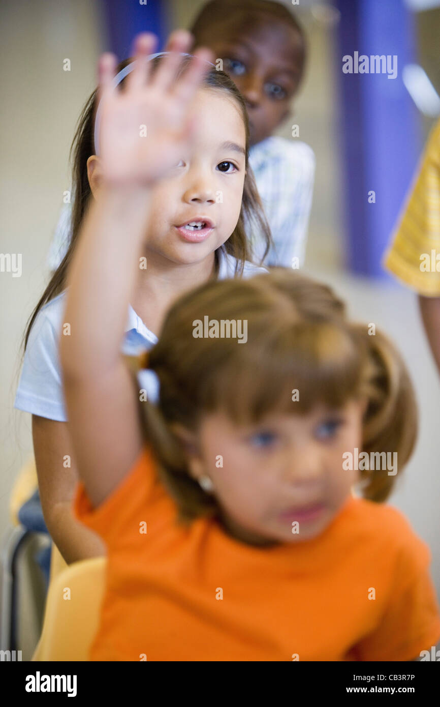 Girl raising hand in a classroom Stock Photo - Alamy