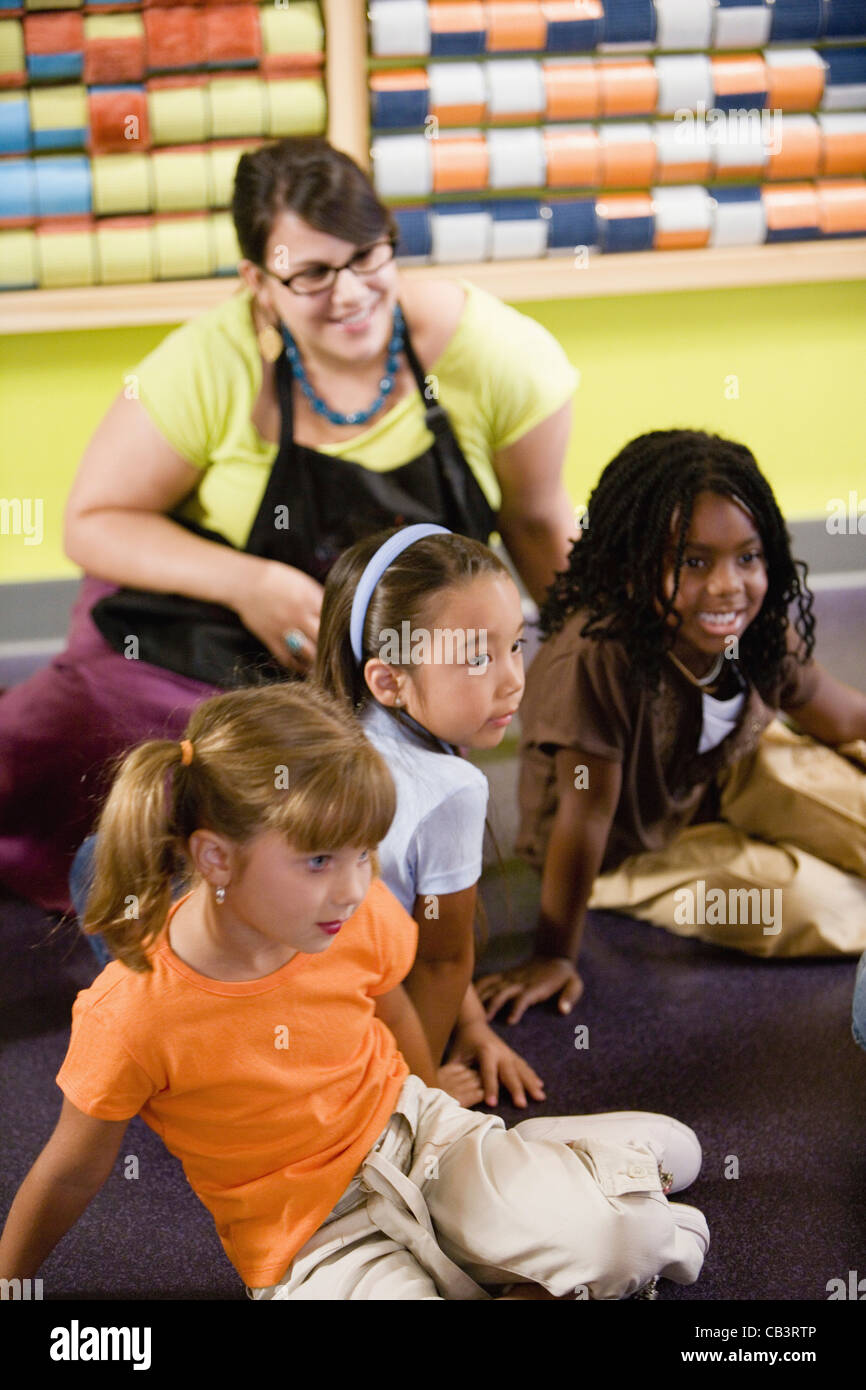Teacher sitting and posing with students in a colorful classroom Stock ...