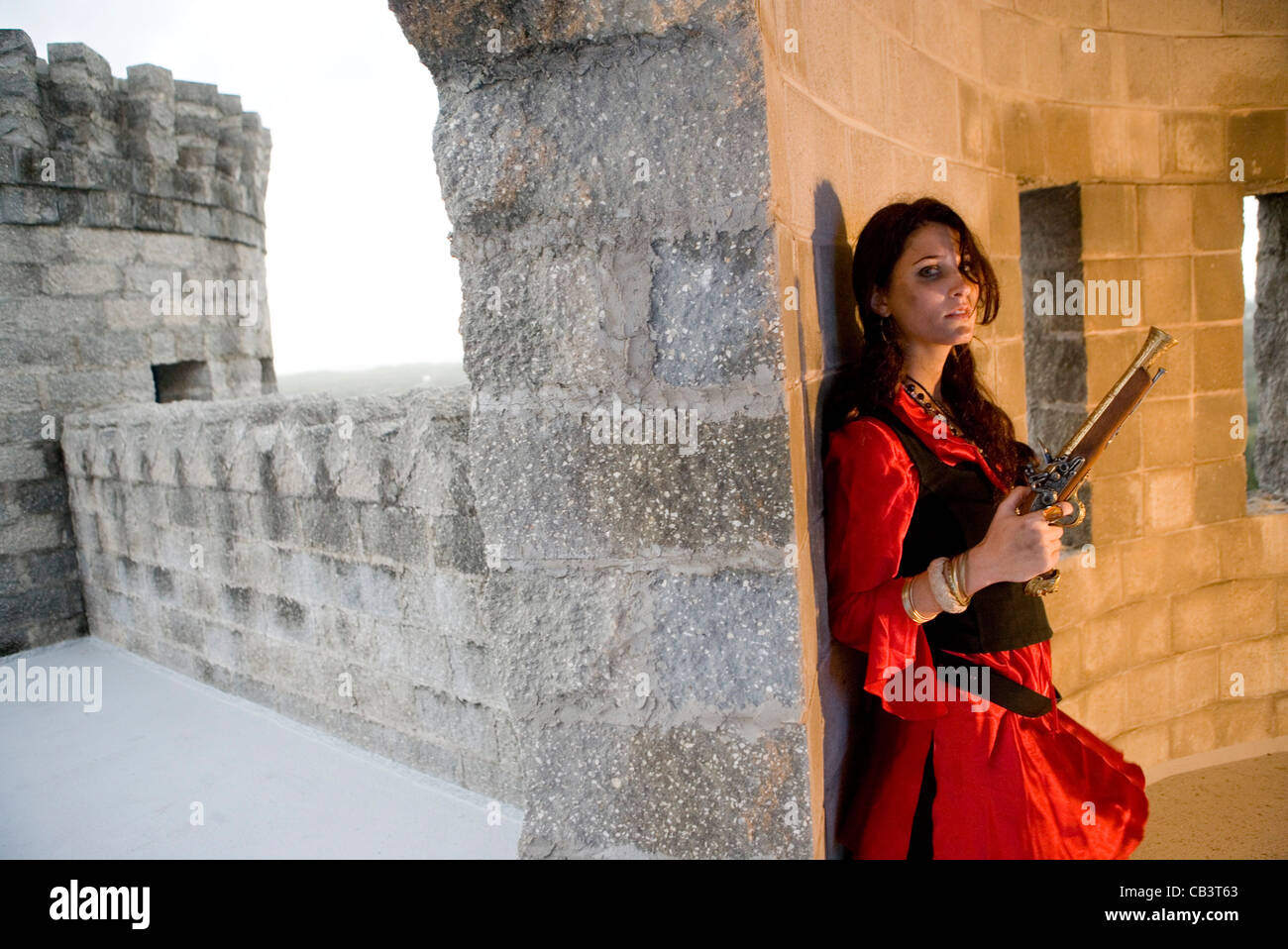 Portrait of a woman pirate armed with a pistol standing inside a castle ...