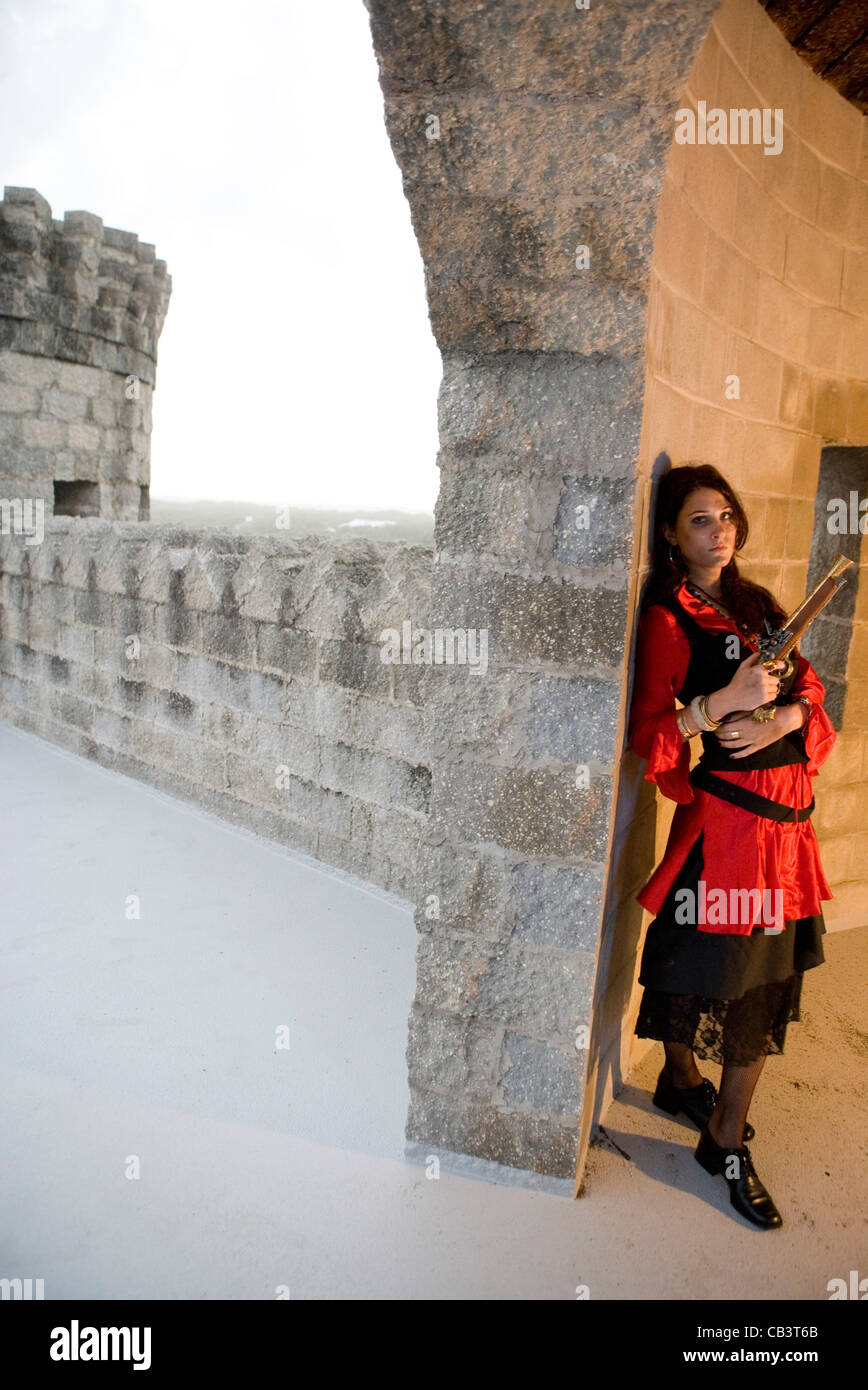 Portrait of a woman pirate armed with a pistol standing inside a castle ...