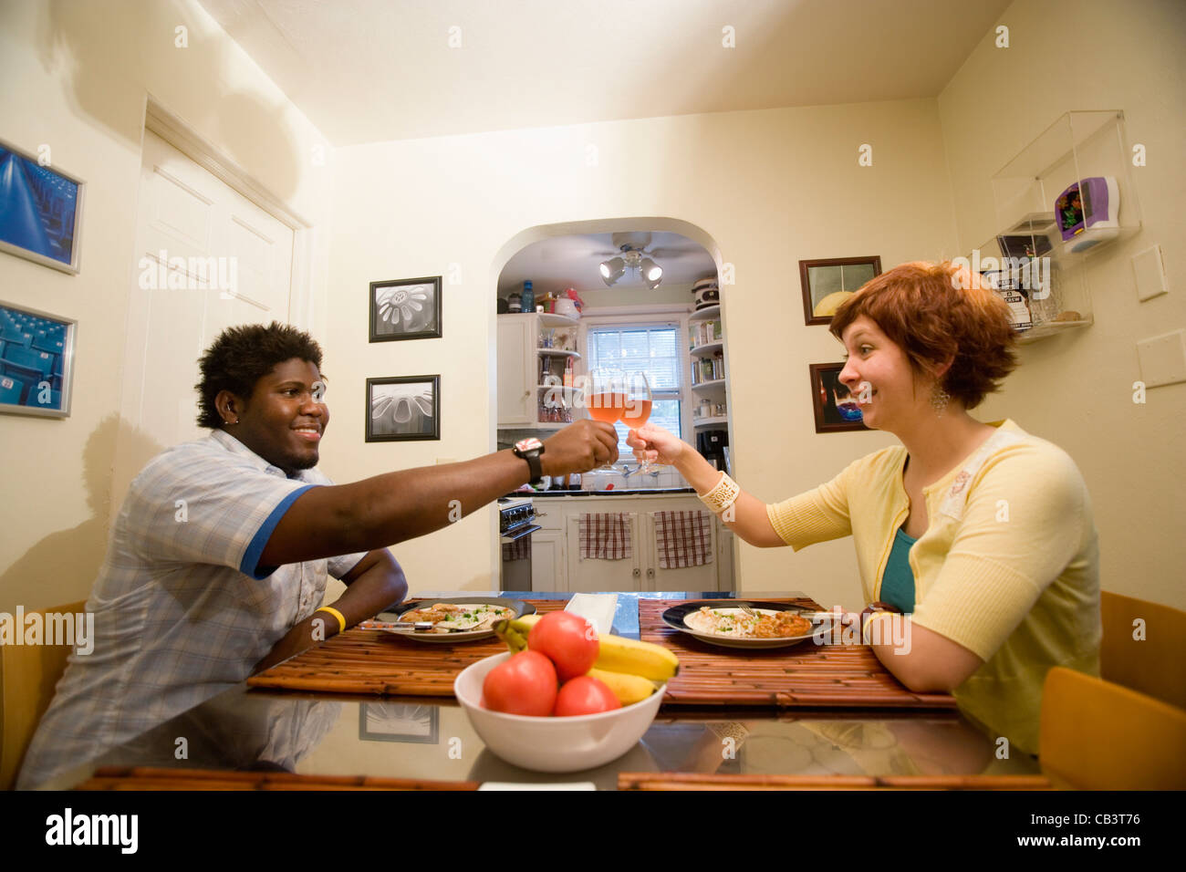 Portrait of a young inter-racial couple sitting at dining table ...