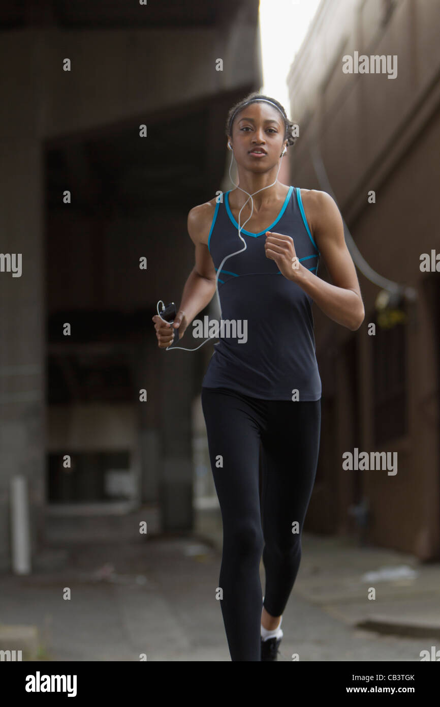 Woman listening to mp3 player while jogging Stock Photo - Alamy