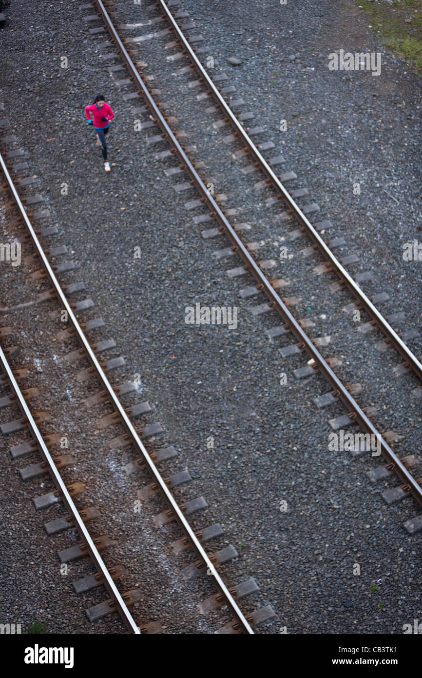 Woman running across railroad tracks Stock Photo - Alamy