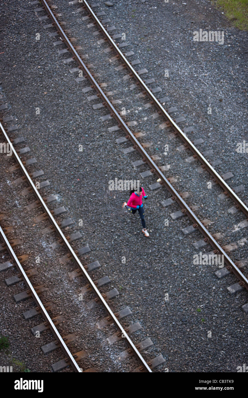 Woman running across railroad tracks Stock Photo - Alamy