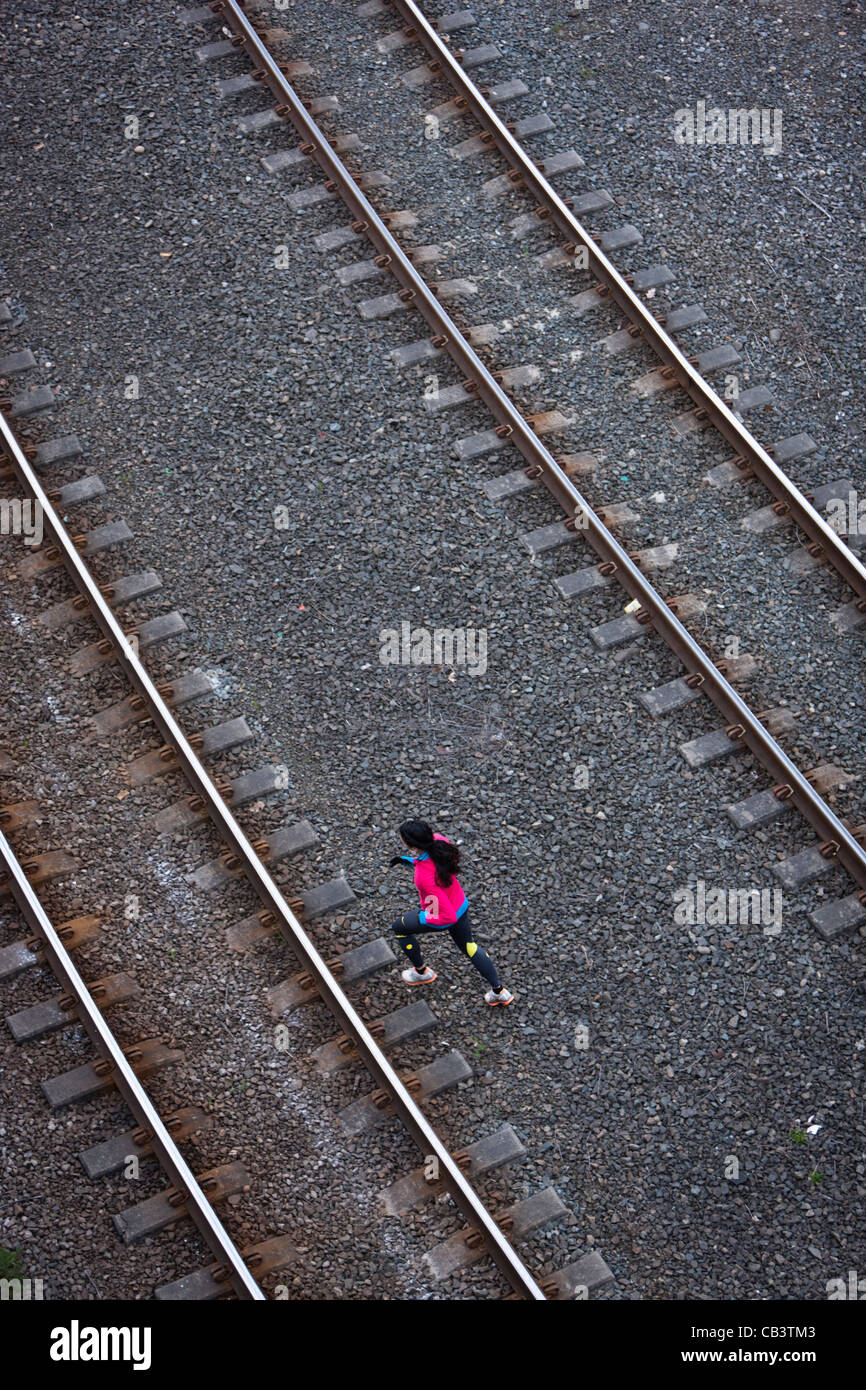 Woman running across railroad tracks Stock Photo - Alamy