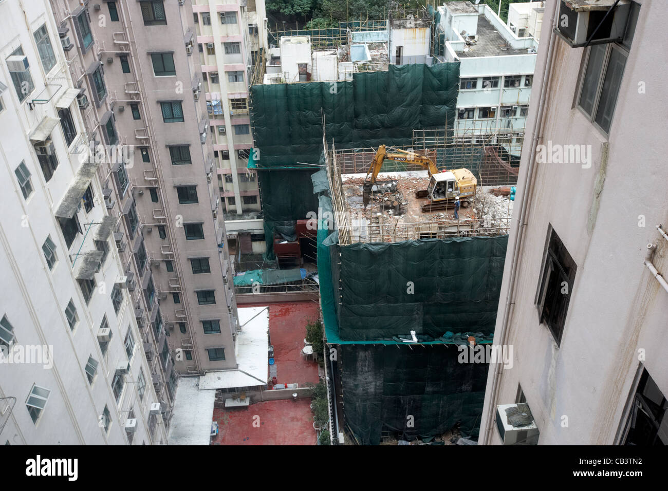 excavator on top of building construction work ongoing in between high ...