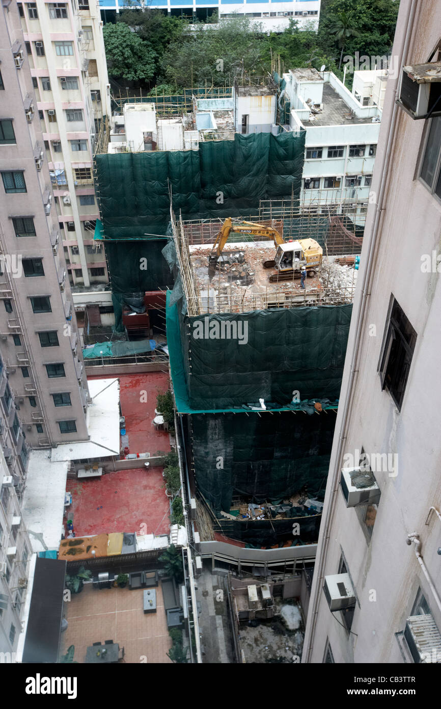 excavator on top of building construction work ongoing in between high ...