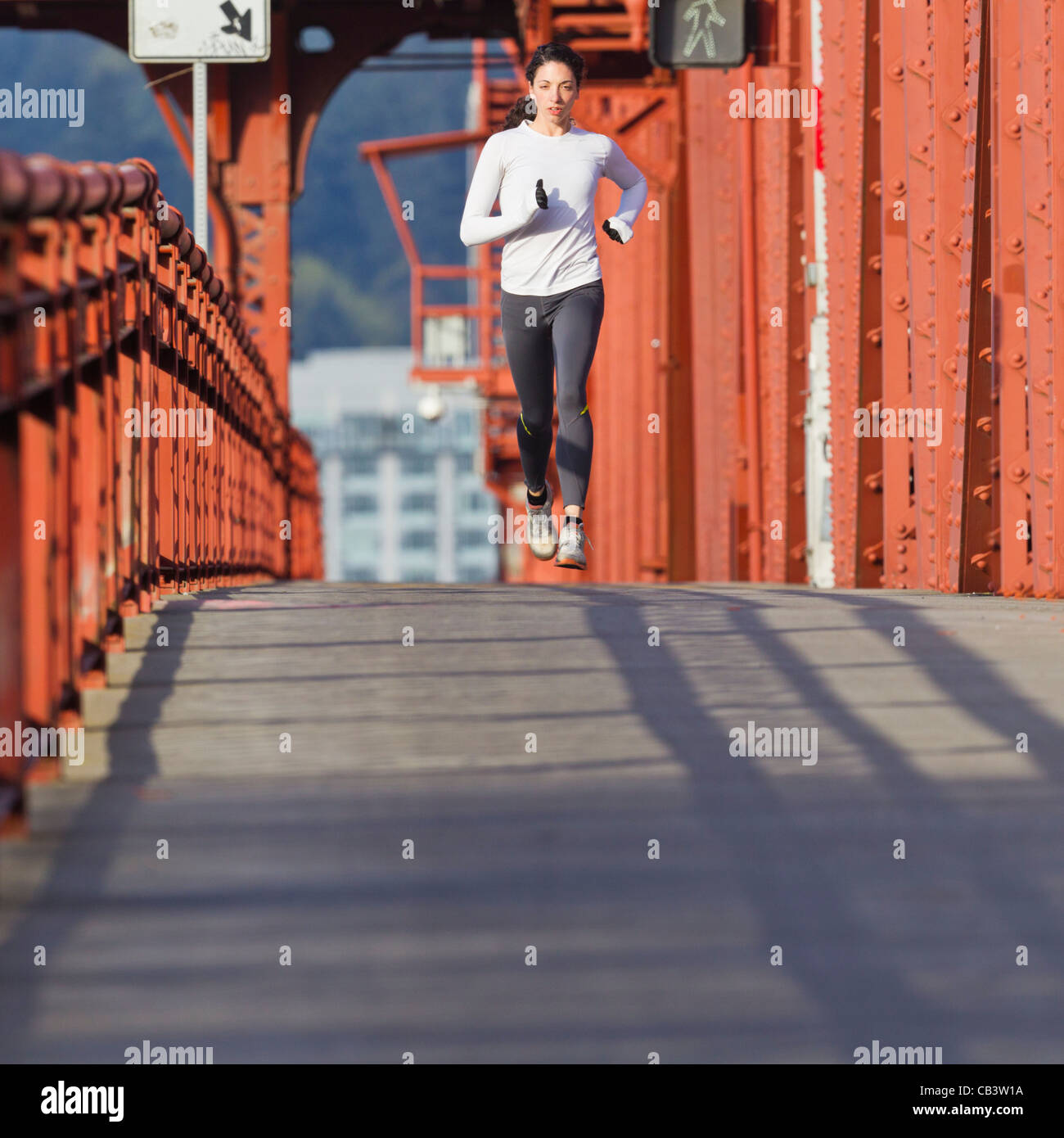 Young woman running along bridge Stock Photo - Alamy