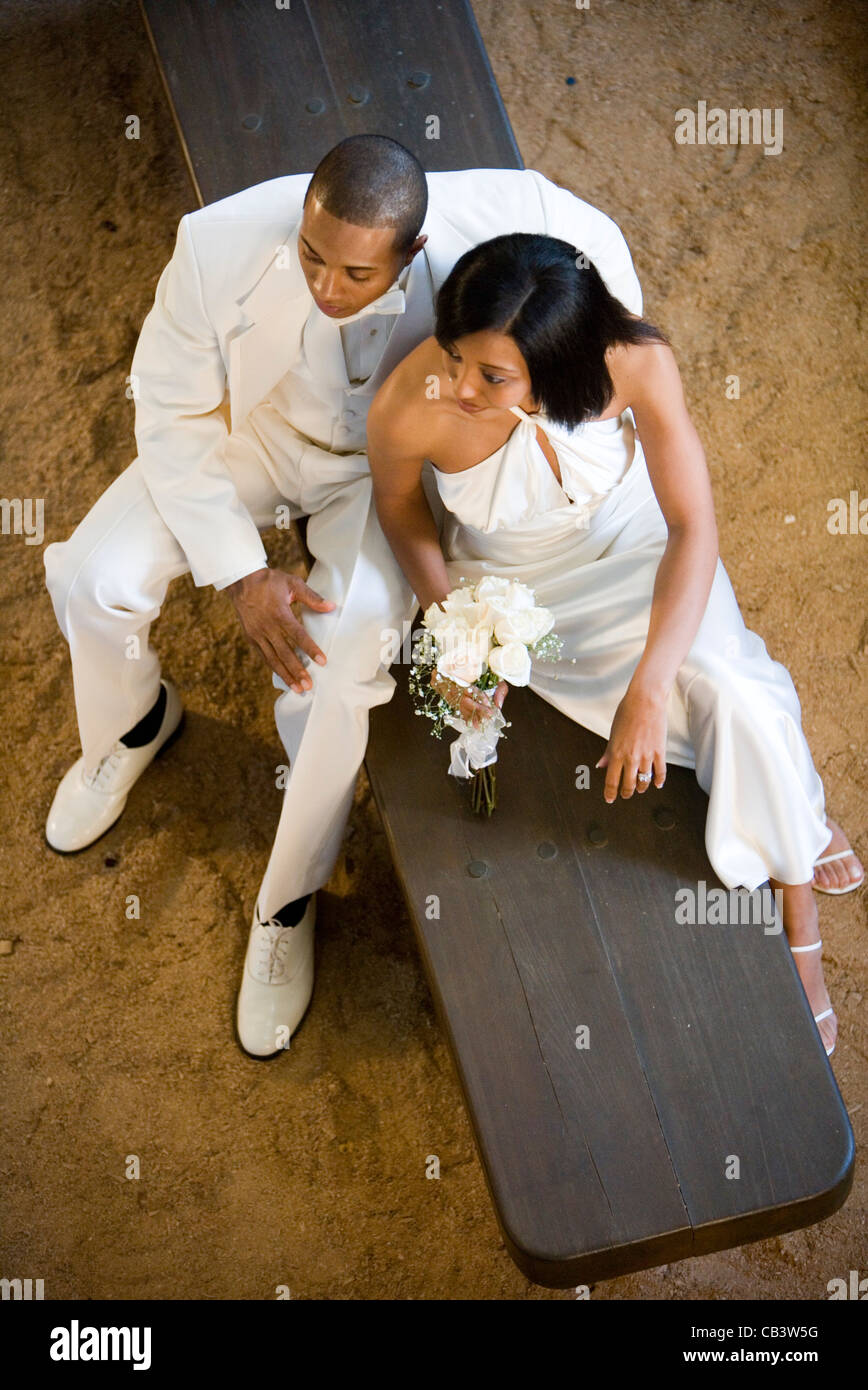 Young bride and groom seated on a bench Stock Photo - Alamy