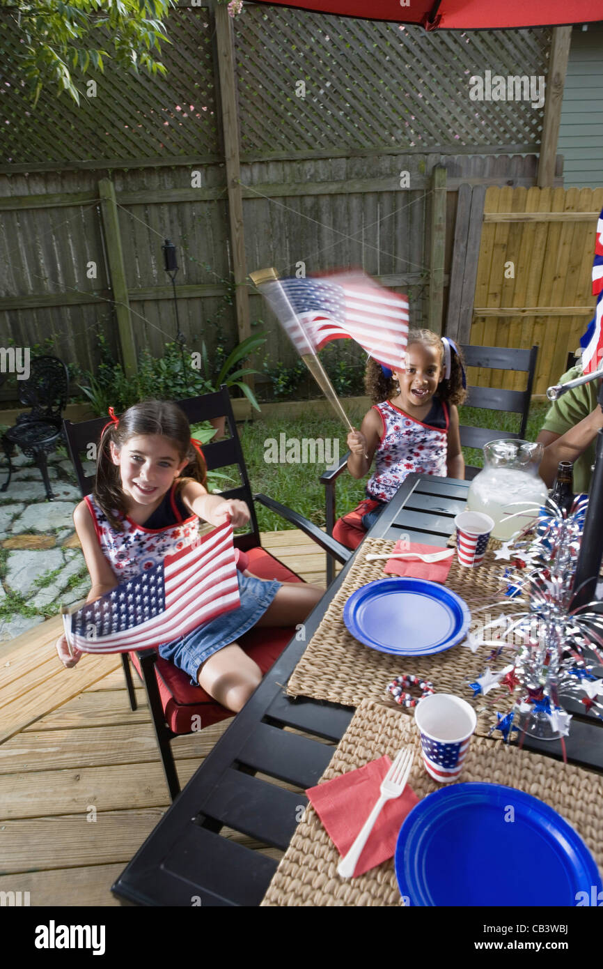 Two young girls at 4th of July cookout waving American flags Stock ...